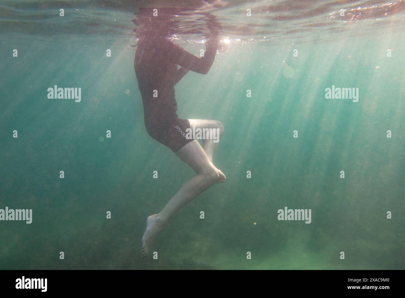 Sun light rays beaming into the blue green water and highlighting the ...