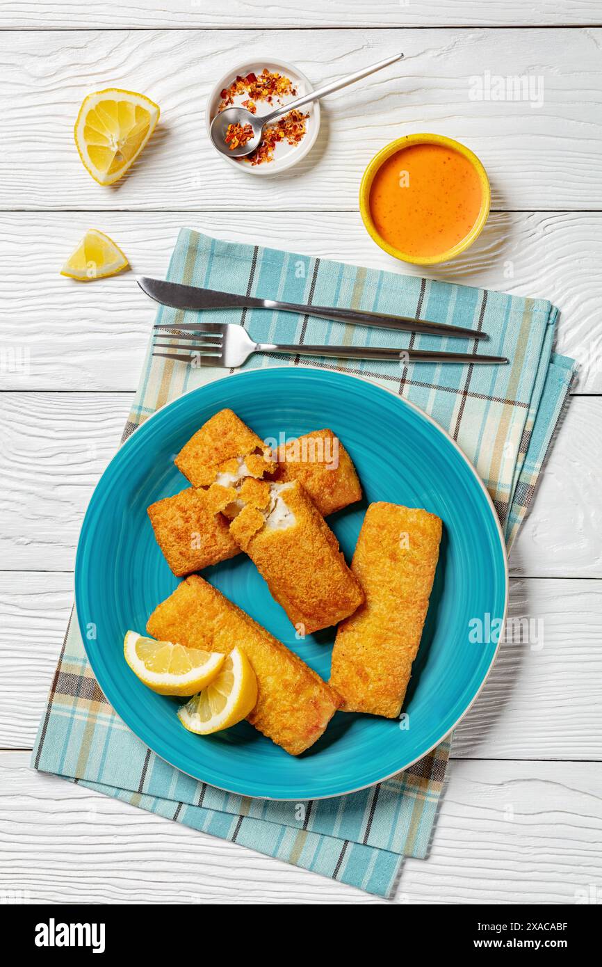 crispy fried battered alaskan pollock fillet on blue dish with lemon ...