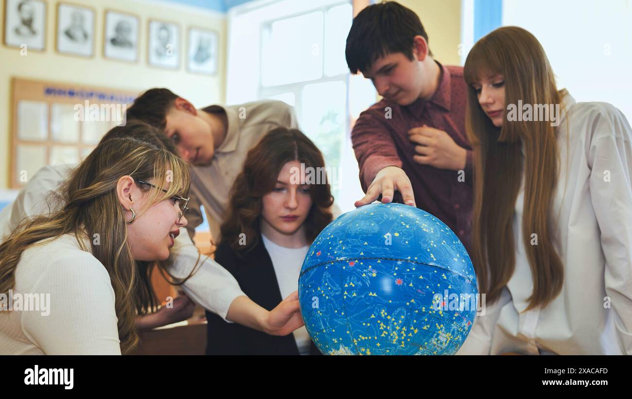 Students look at a globe of the starry sky in a classroom at school ...