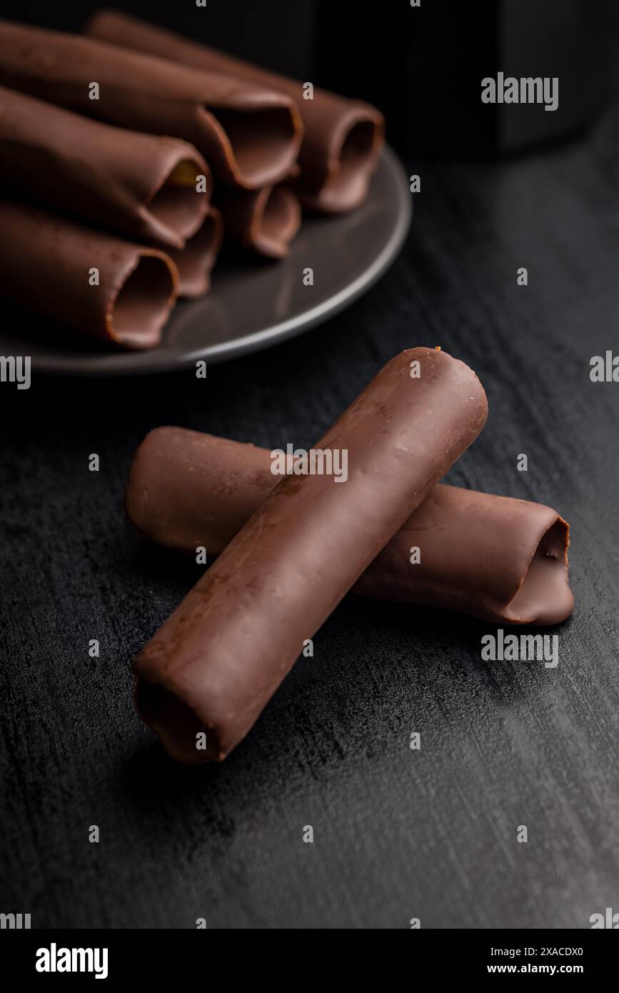 A close-up shot of chocolate covered wafers lying on a dark table. The ...