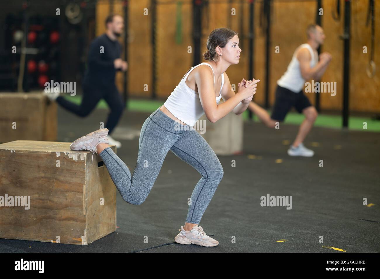 Concentrated girl performing Bulgarian split squats on box at gym Stock ...