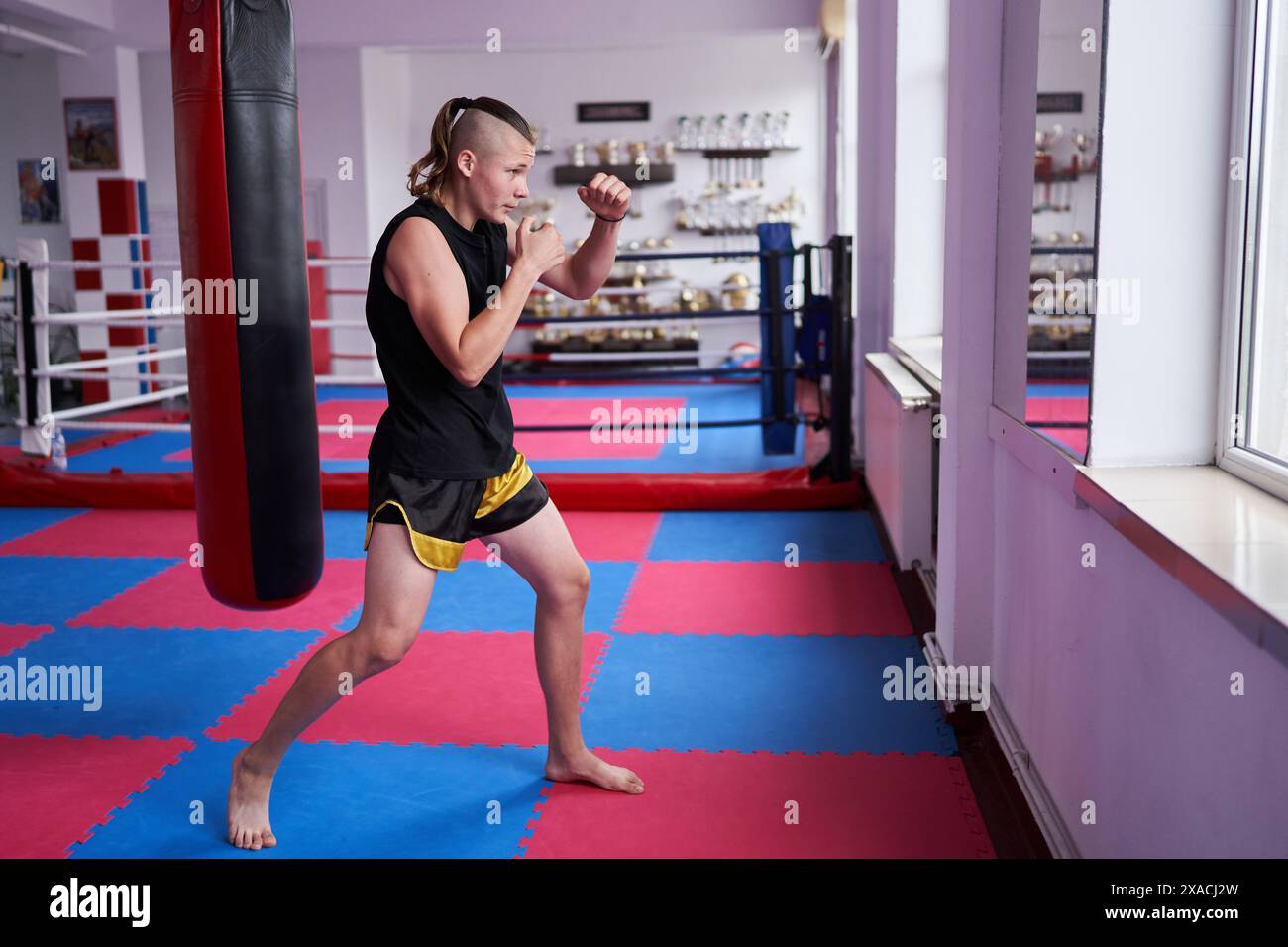 Young teenage kickbox fighter doing shadow boxing drills in a gym as ...
