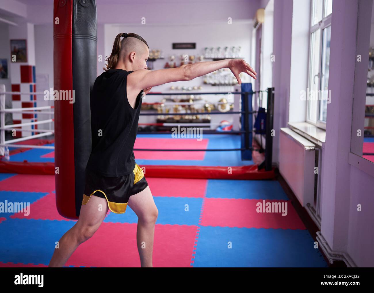 Young teenage kickbox fighter doing shadow boxing drills in a gym as ...