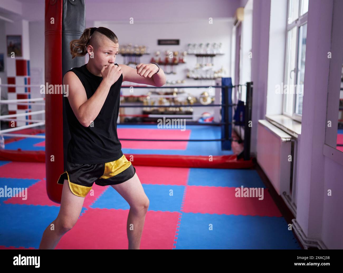 Young teenage kickbox fighter doing shadow boxing drills in a gym as ...