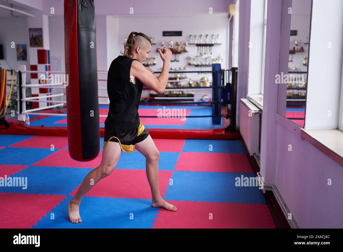 Young teenage kickbox fighter doing shadow boxing drills in a gym as ...