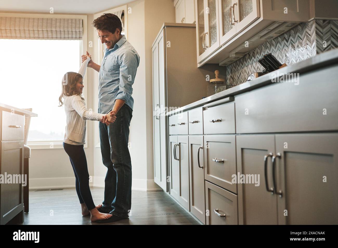 Dancing, kitchen and child on feet of father listening to music ...