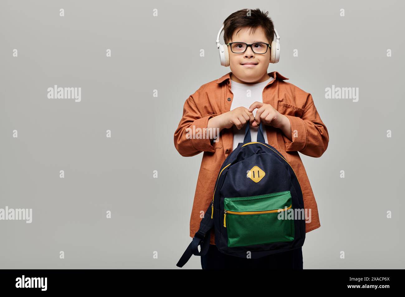 little kid with Down syndrome wearing headphones, holding a backpack ...