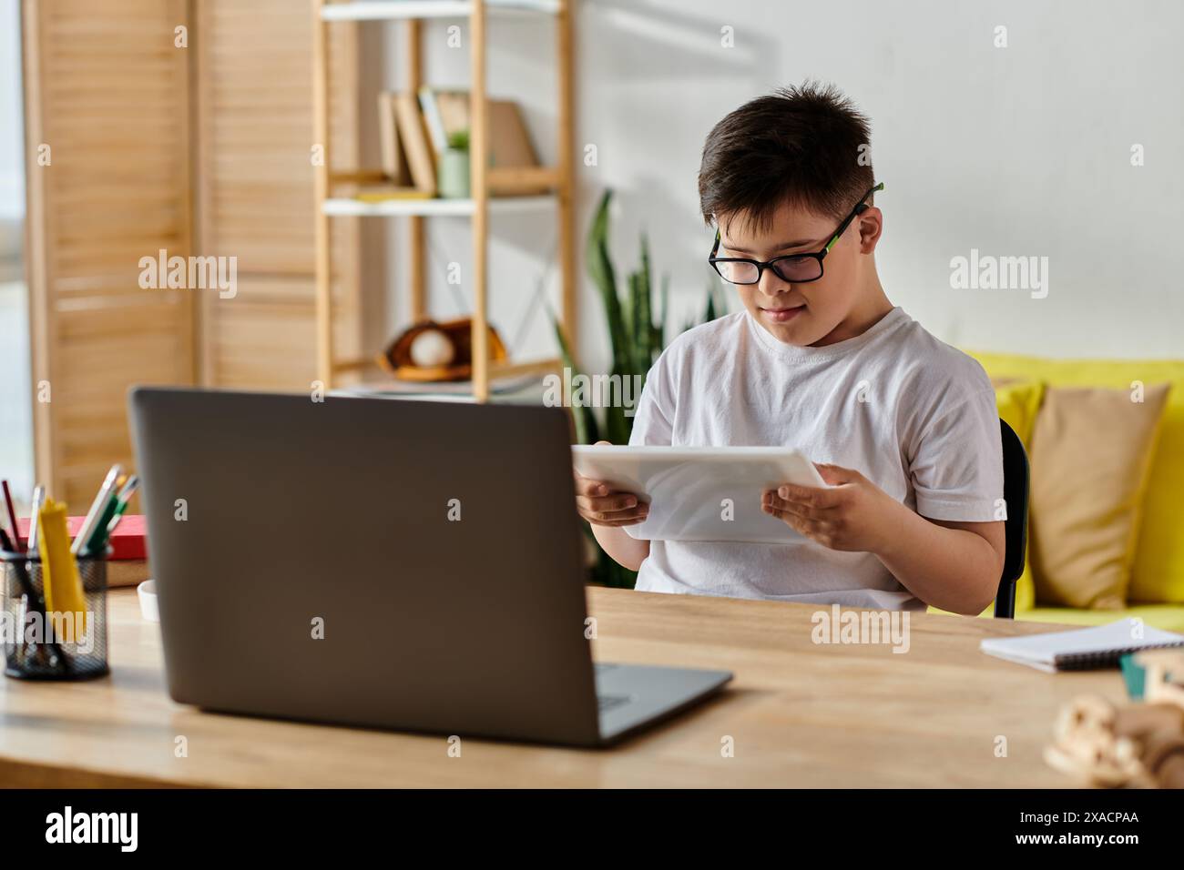 adorable boy with Down syndrome with glasses immersed in laptop ...