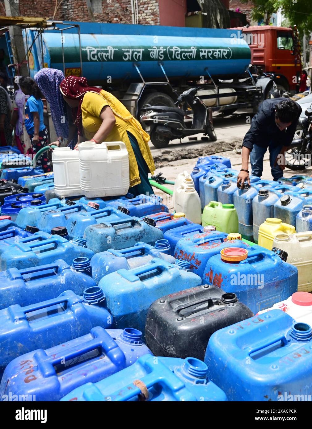 NEW DELHI, INDIA - JUNE 5: residents fill empty containers from a water tanker at Kusumpur ...