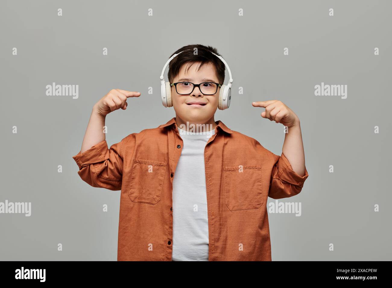 little child with Down syndrome wearing headphones, pointing to his ...