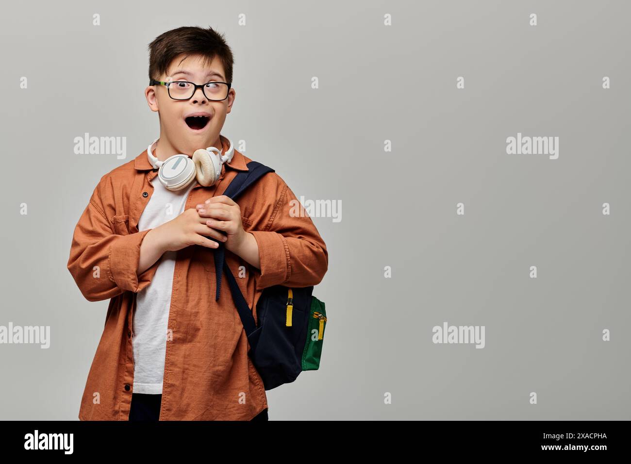 A little kid with Down syndrome with glasses and a backpack explores ...