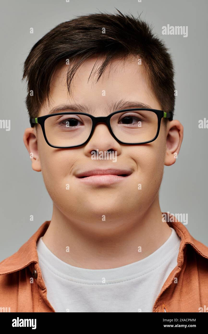 Charming little boy with Down syndrome smiling warmly at the camera ...