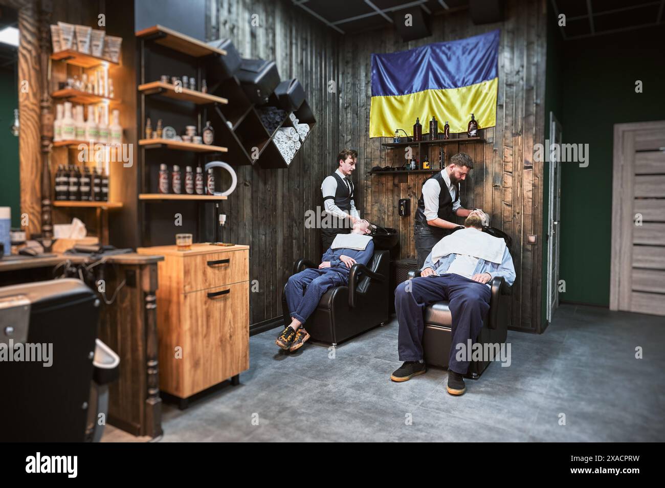 Professional barbers washing hair with deep cleaning shampoo. Busy day ...
