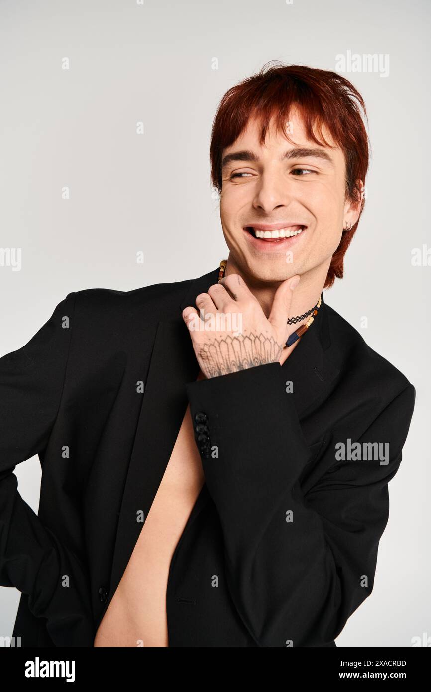 A stylish young man in a black suit strikes a confident pose against a ...