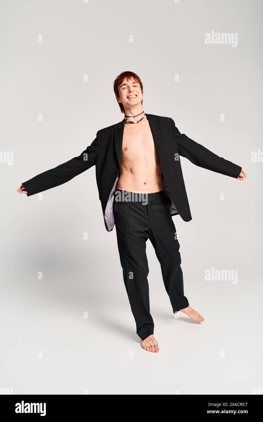 A stylish young man in a suit strikes a confident pose in a studio with ...