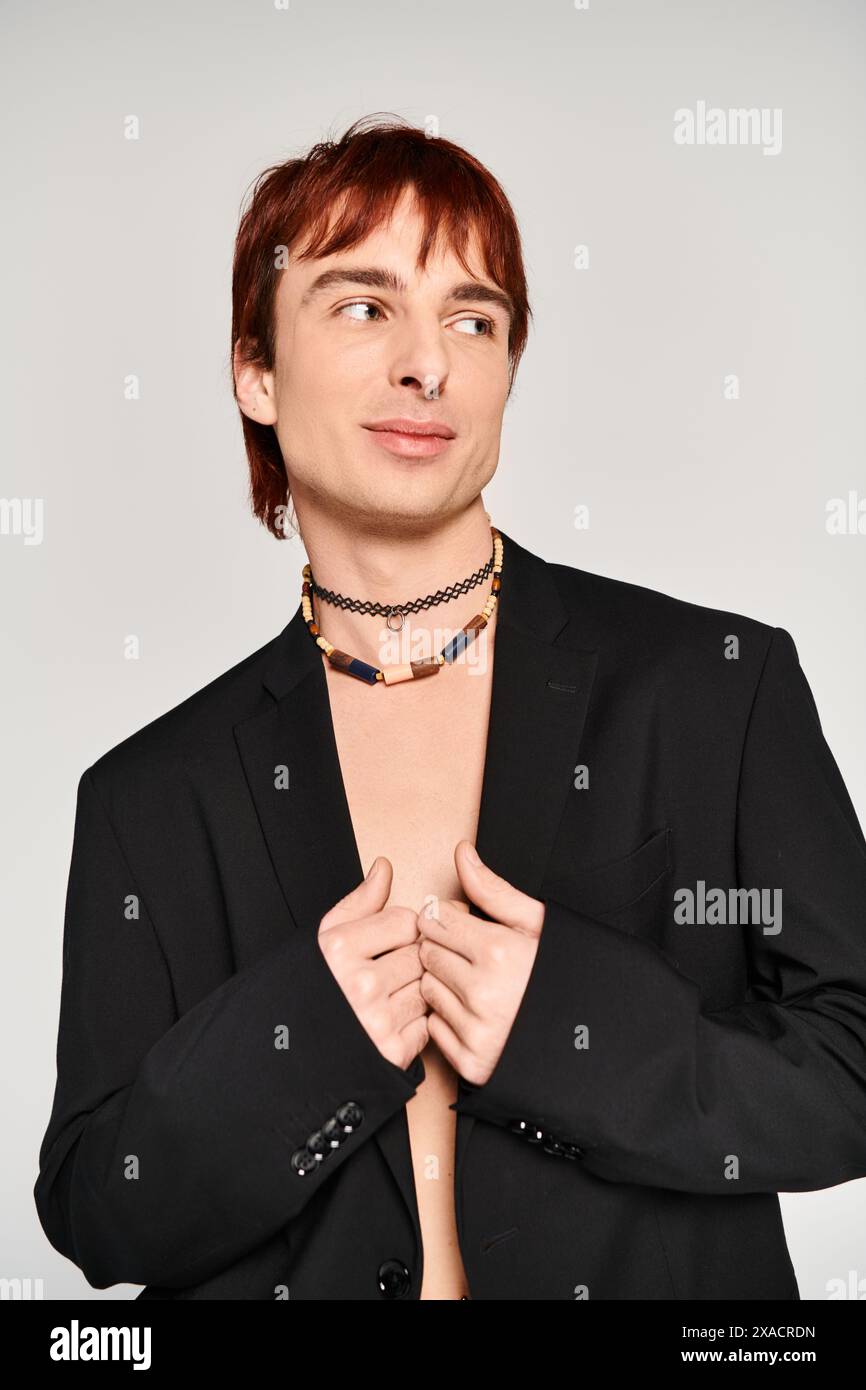 A stylish young man in a black suit striking a pose with a chain around ...