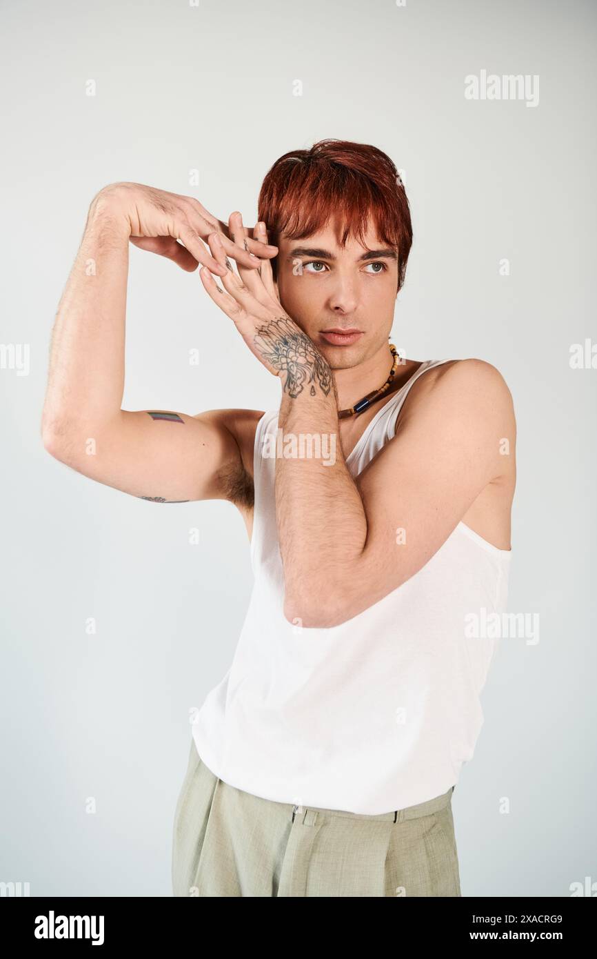 A stylish young man in a tank top strikes a confident pose against a ...