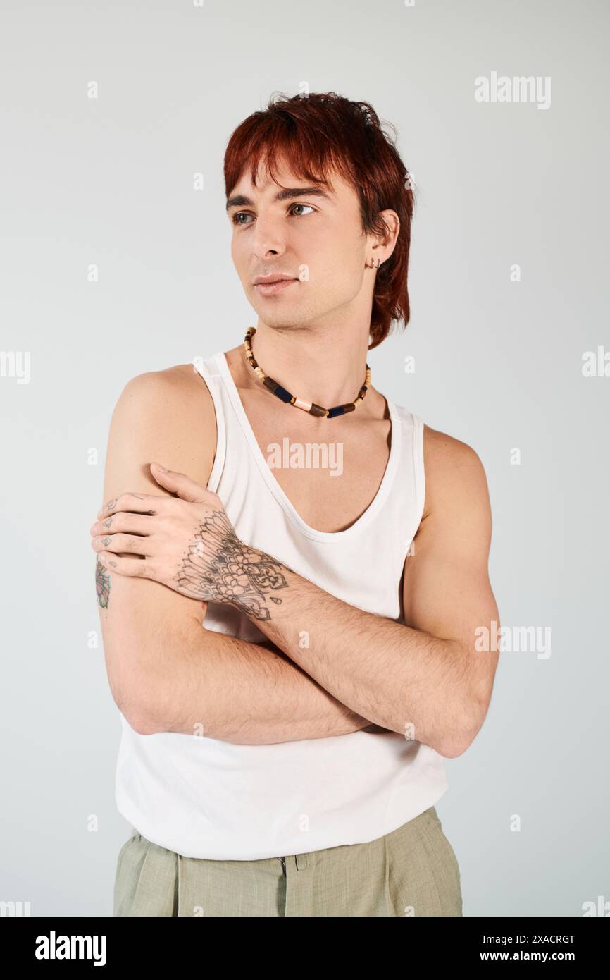 Trendy young man with vibrant red hair strikes a pose in a white tank ...