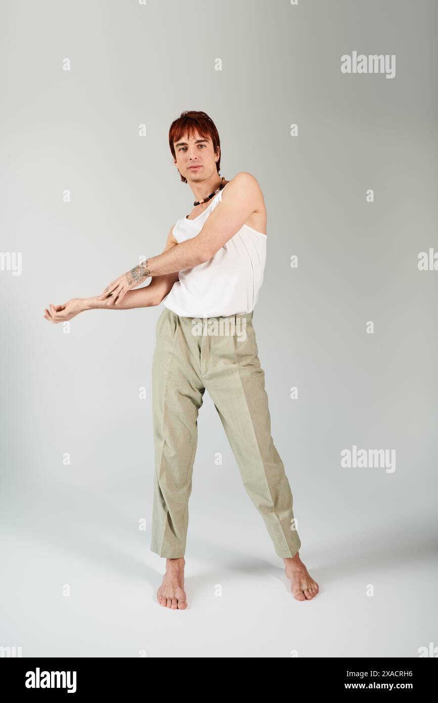 Stylish young man strikes a pose in studio setting, wearing white tank ...