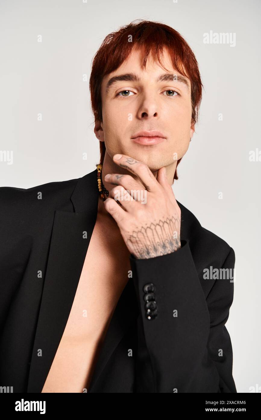 A stylish young man in a black suit striking a confident pose against a ...