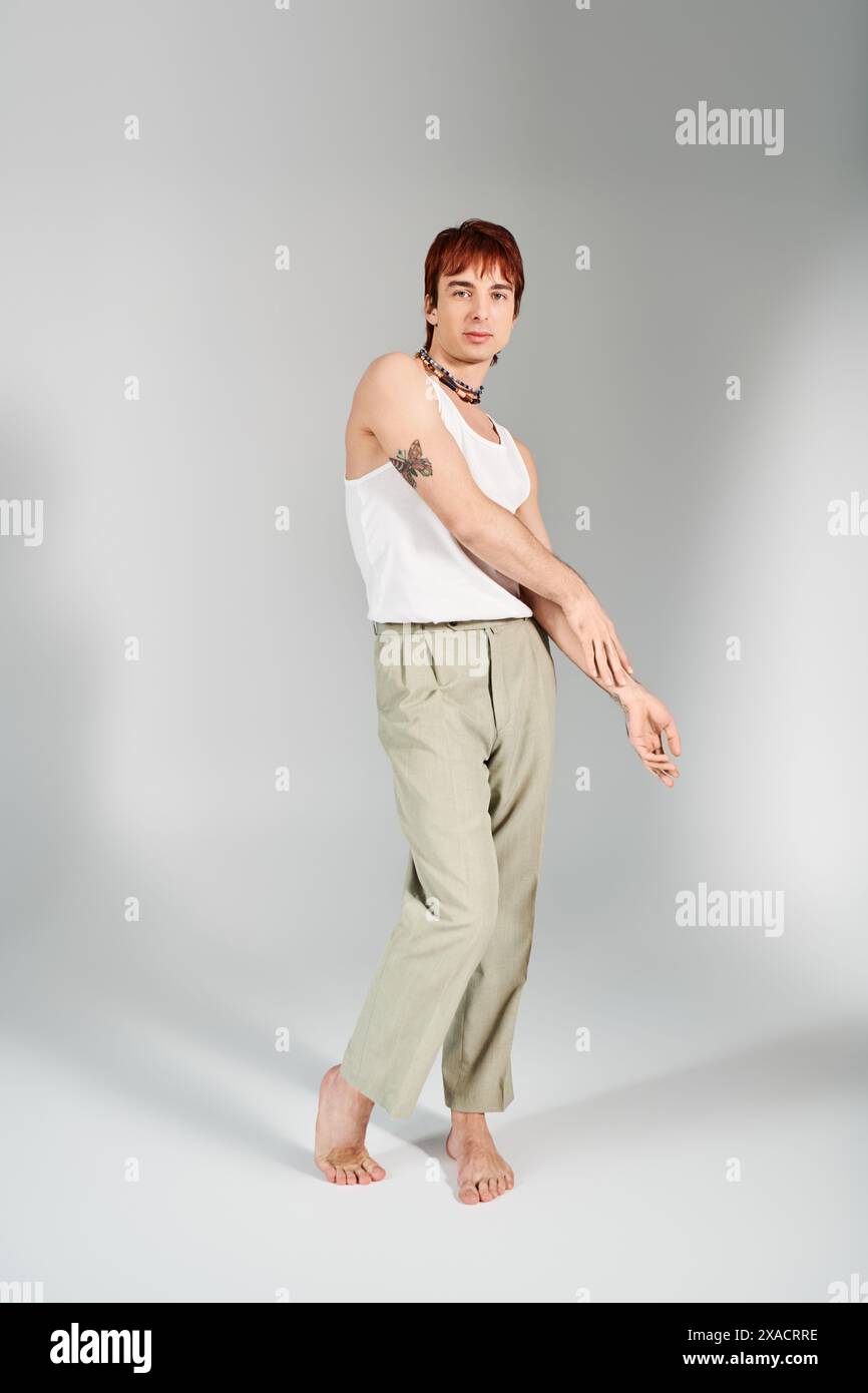 A stylish young man poses in a studio against a grey background ...