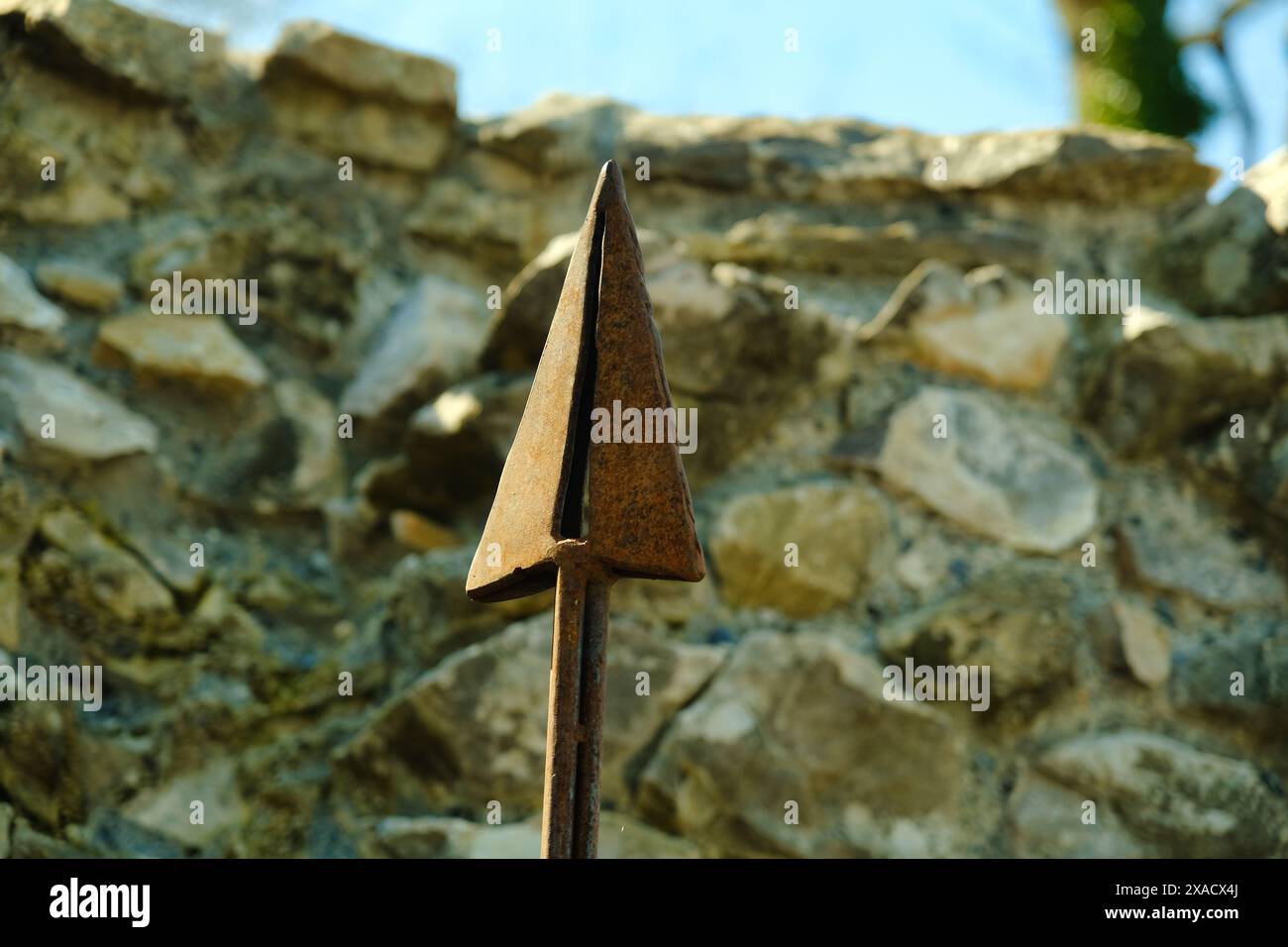 A rusty arrow is stuck in a stone wall. The arrow is bent and twisted ...