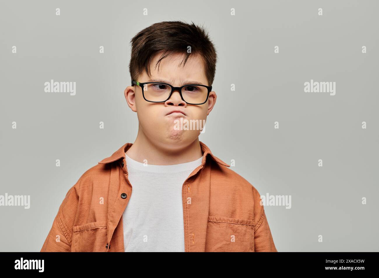A little boy with Down syndrome with glasses showcasing his playful and ...