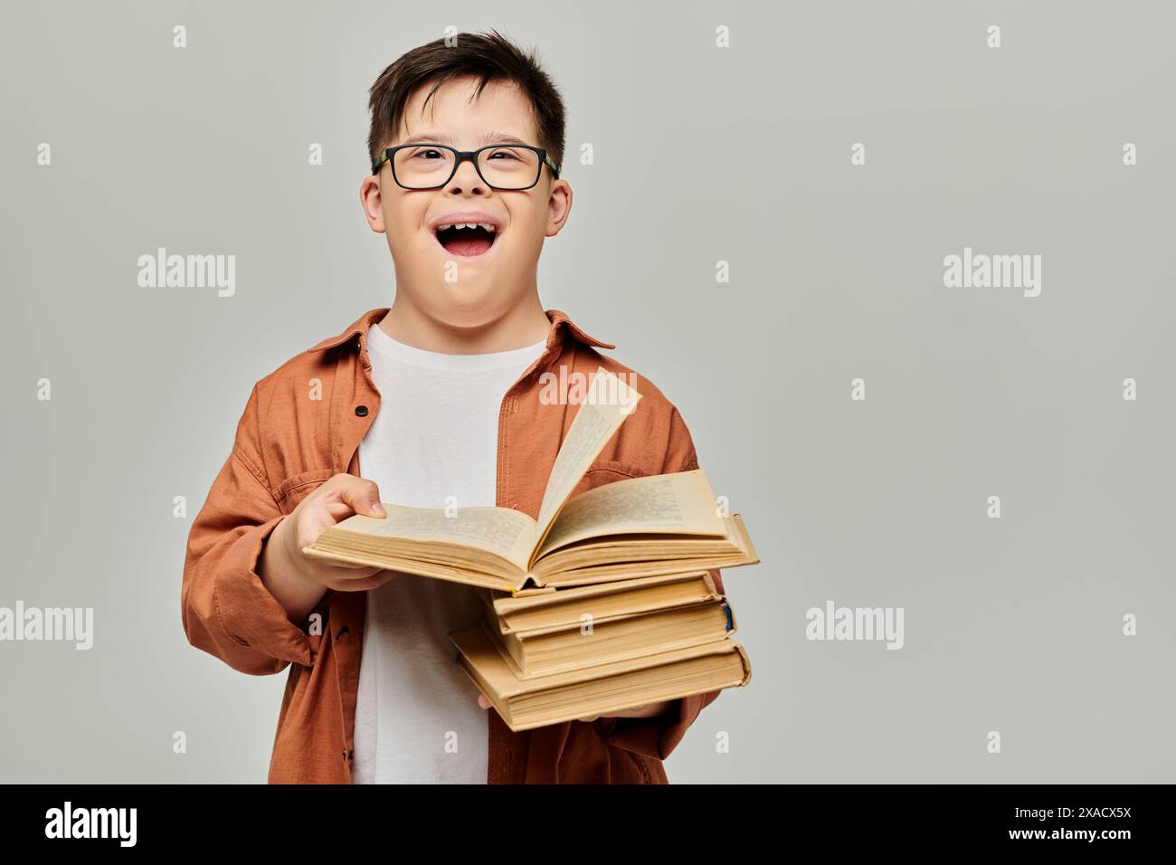 little boy with Down syndrome with glasses cheerfully holds a tall ...