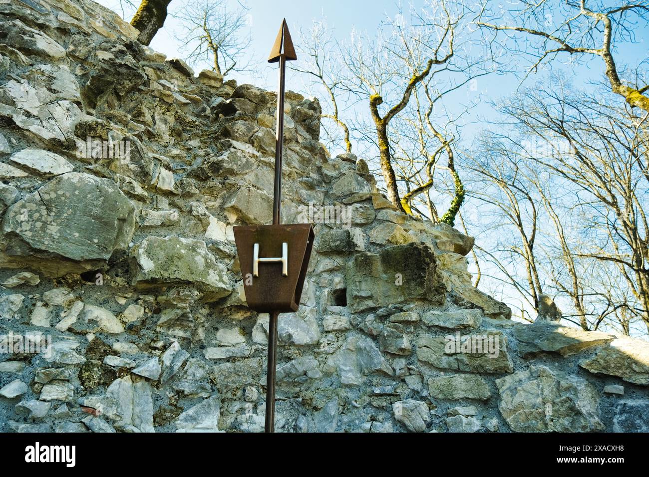 A metal arrow is stuck into a stone wall. The arrow is pointing to the ...