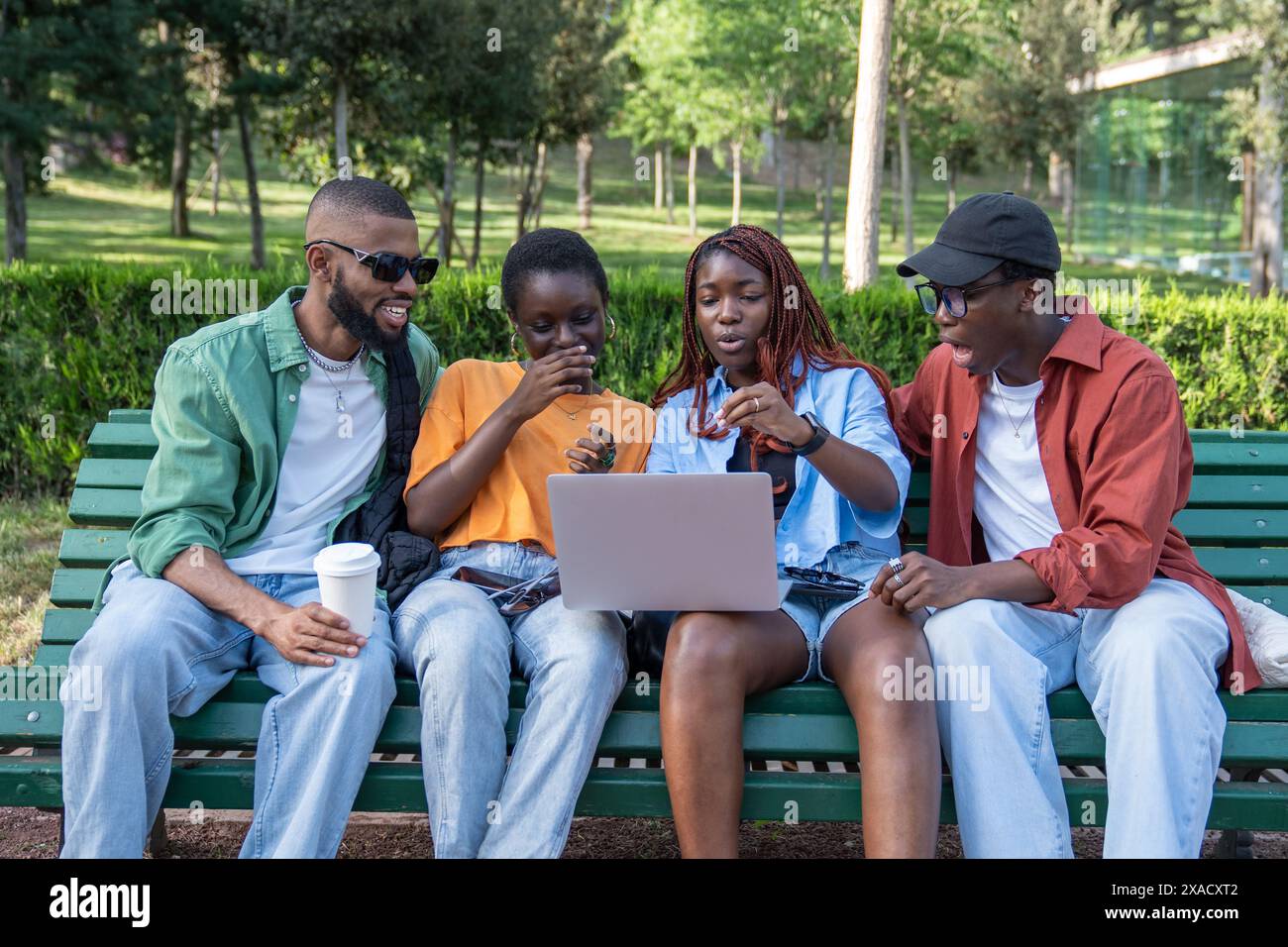 Happy black friends spending time together in nature, using portable ...