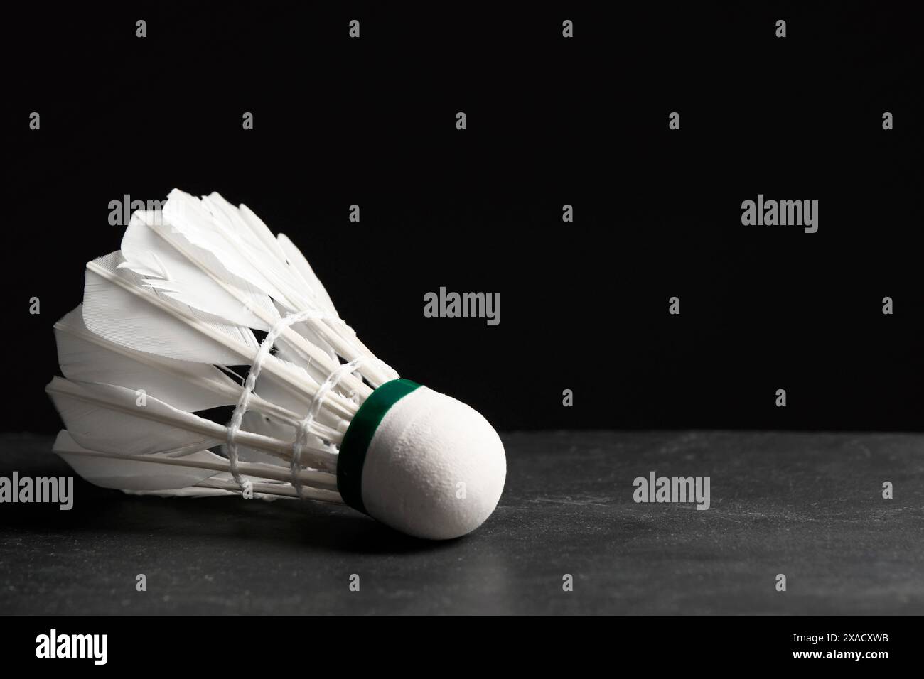 Feather badminton shuttlecock on grey table against black background ...