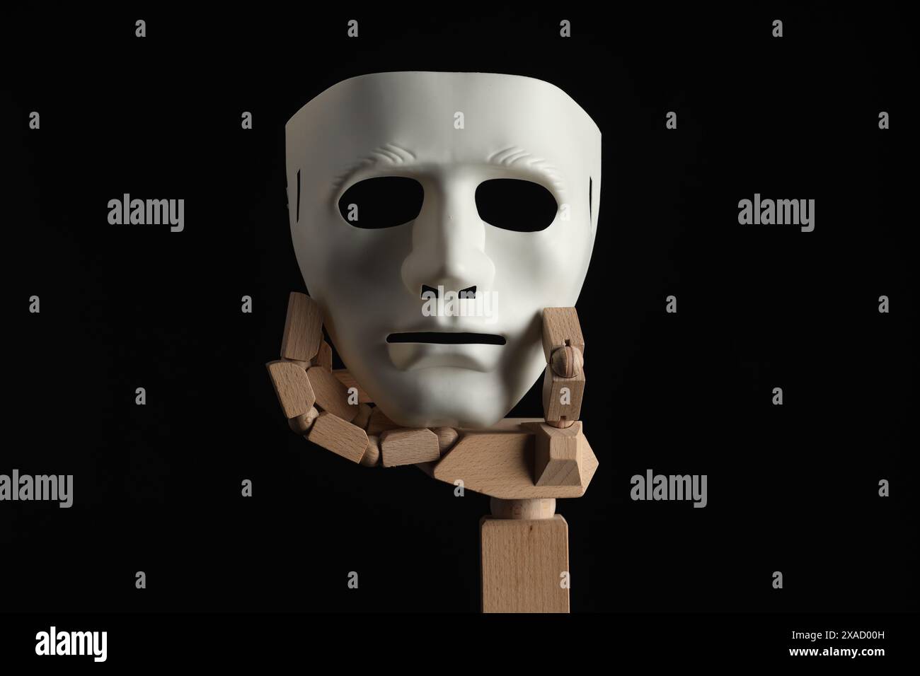 Wooden mannequin hand holding plastic mask on black background ...
