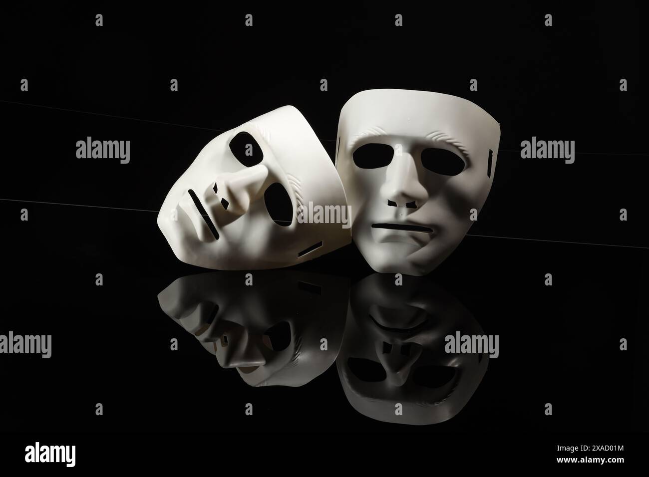 Plastic face masks on black mirror surface. Theatrical performance ...
