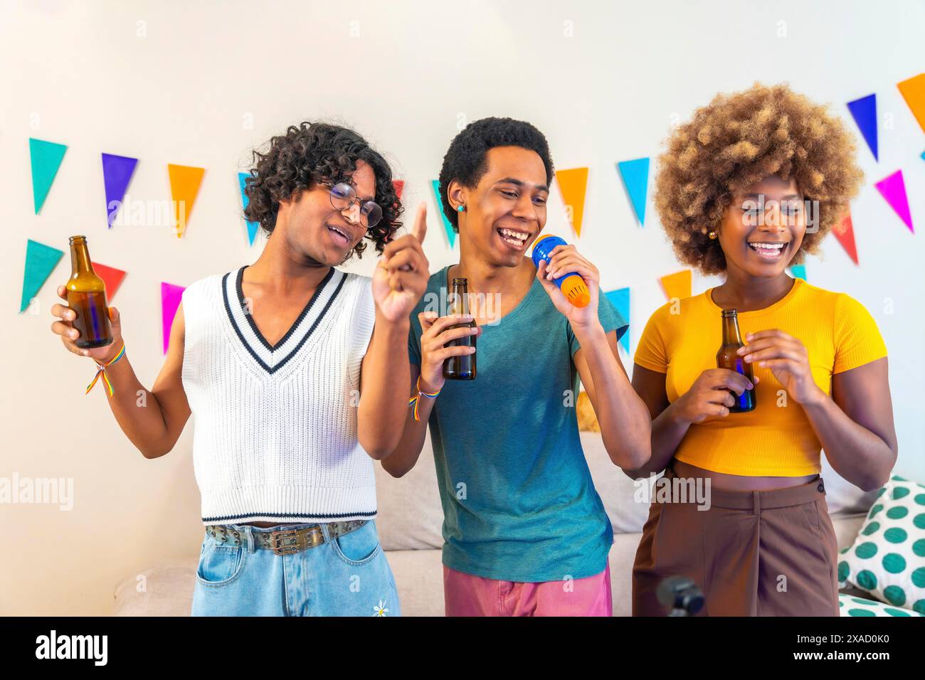 Happy multi-ethnic friends singing karaoke in a living room with party ...