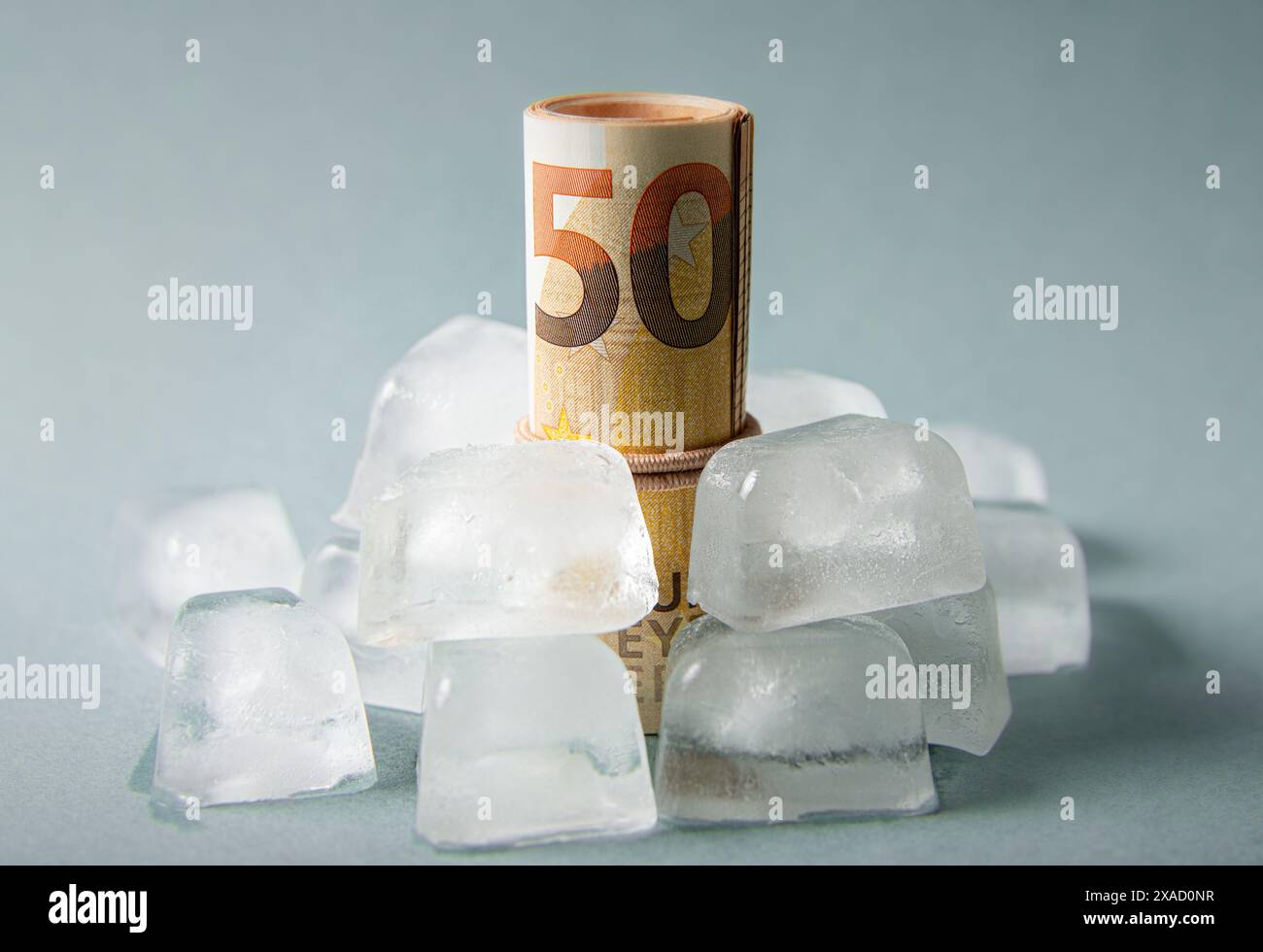 Concept of freezing the funds. Euro money roll inside ice cubes on blue ...