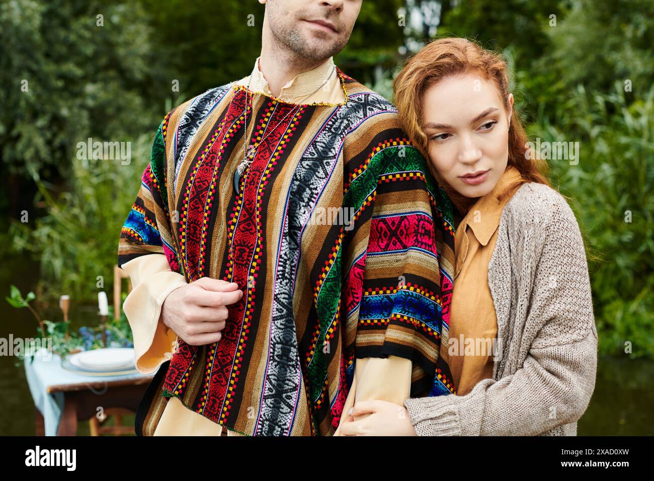 A man and woman in boho style clothing stand closely together in a ...