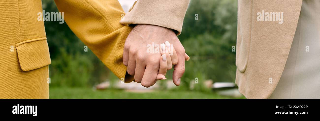 A close-up of two people holding hands, their fingers intertwined in a ...