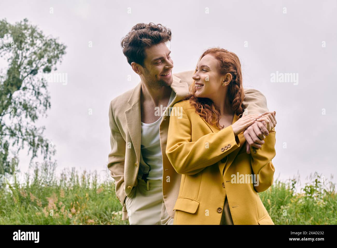 A man and a woman stand together in a lush field, enjoying a serene ...