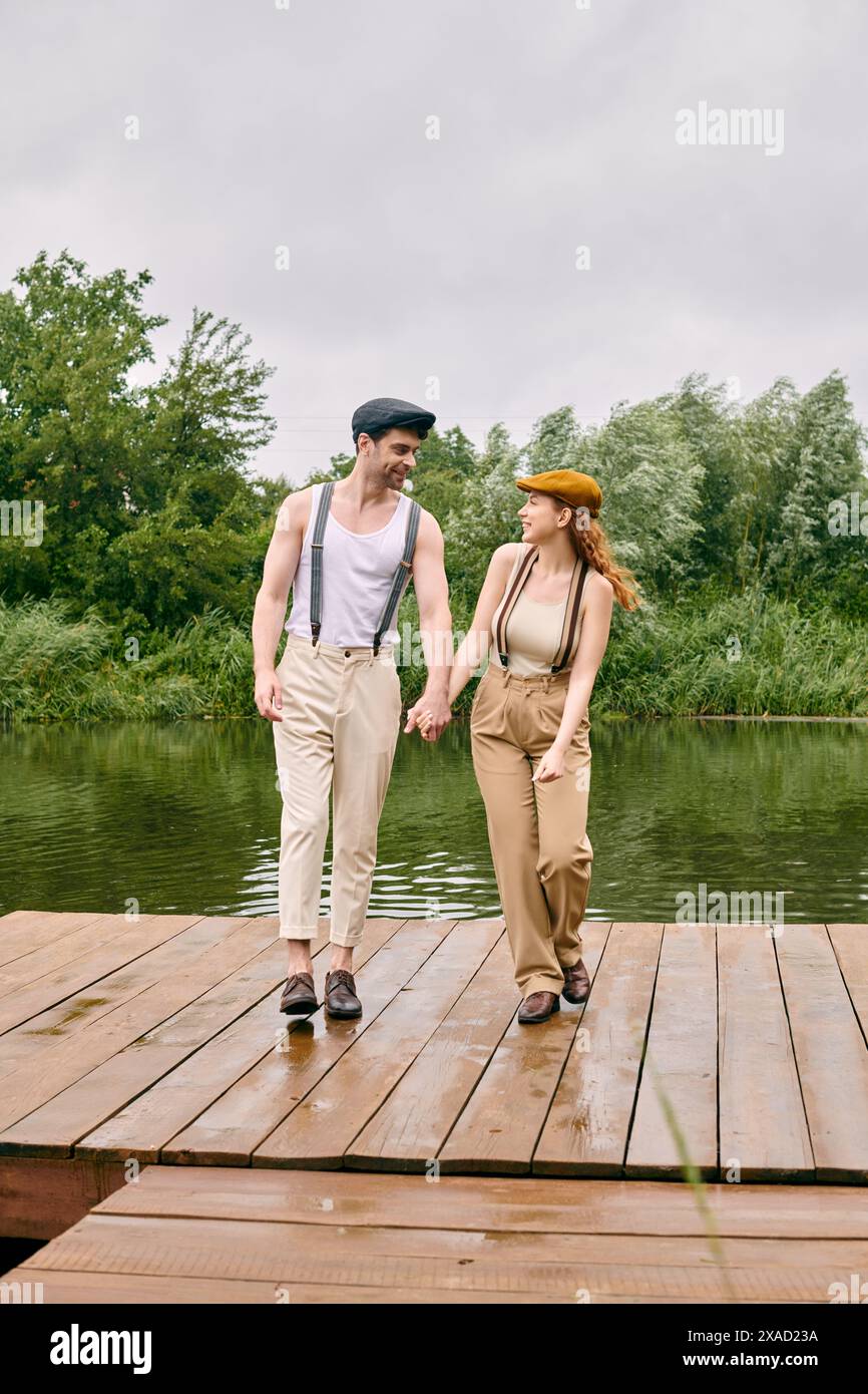 A man and woman, dressed casually, stroll hand in hand across a rustic ...
