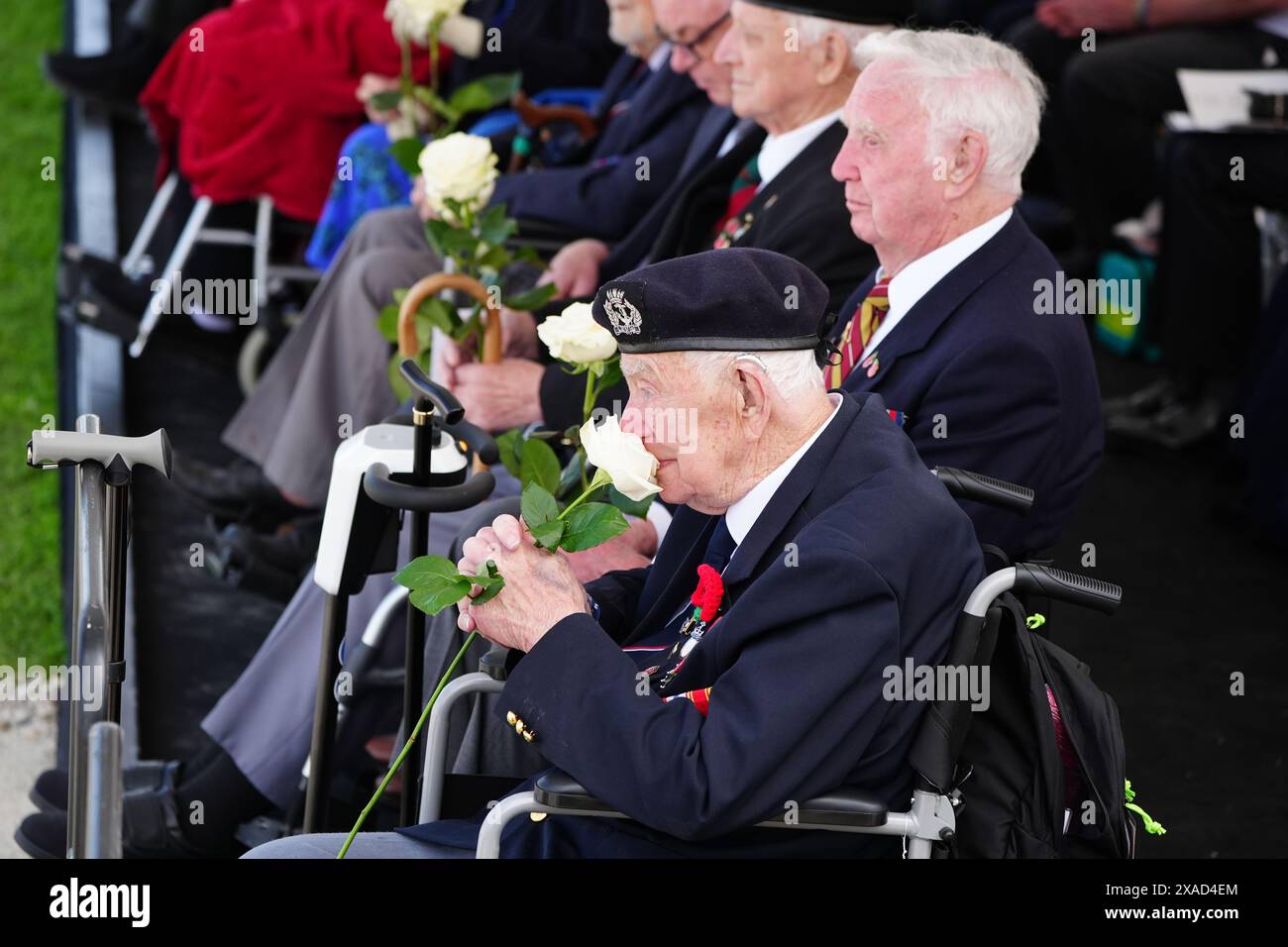 Veterans, including Henry Rice (front), holding roses which they ...