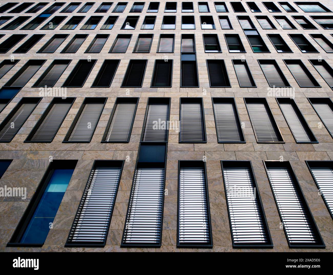 looking upwards at the beige marble facade of a modern office building ...