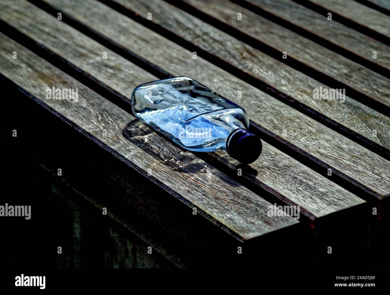 sun-flooded empty small bottle of booze made of blue glass laying on a ...