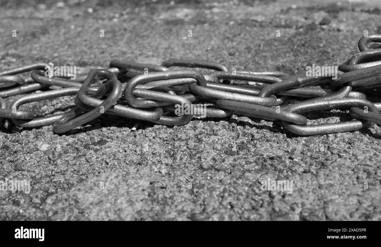 Detail of a metal chain lying on the ground, black and white photograph ...