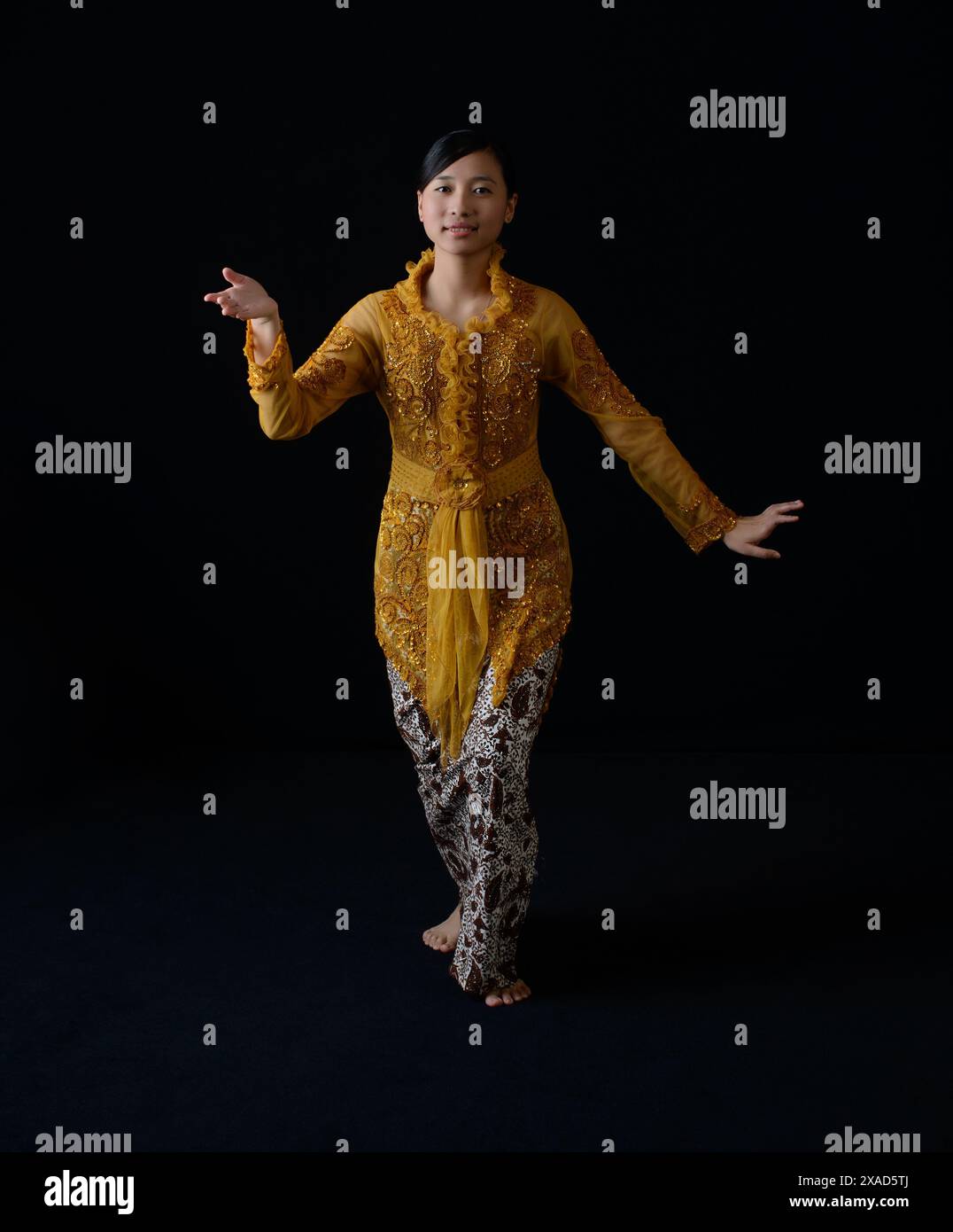 Indonesian woman performing a traditional dance in elaborate golden ...