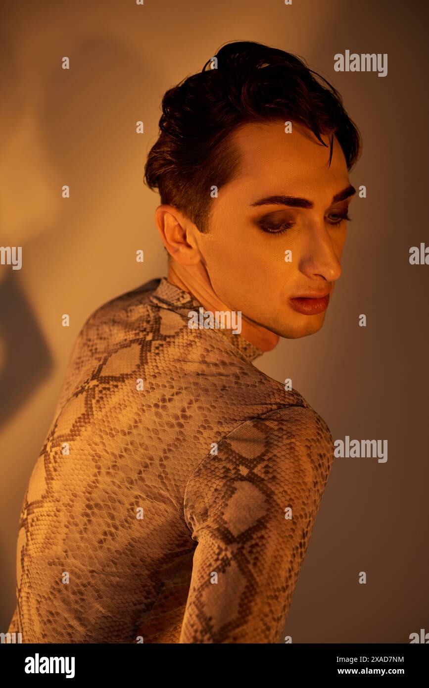 A young queer person poses in front of a mirror wearing a python skin ...
