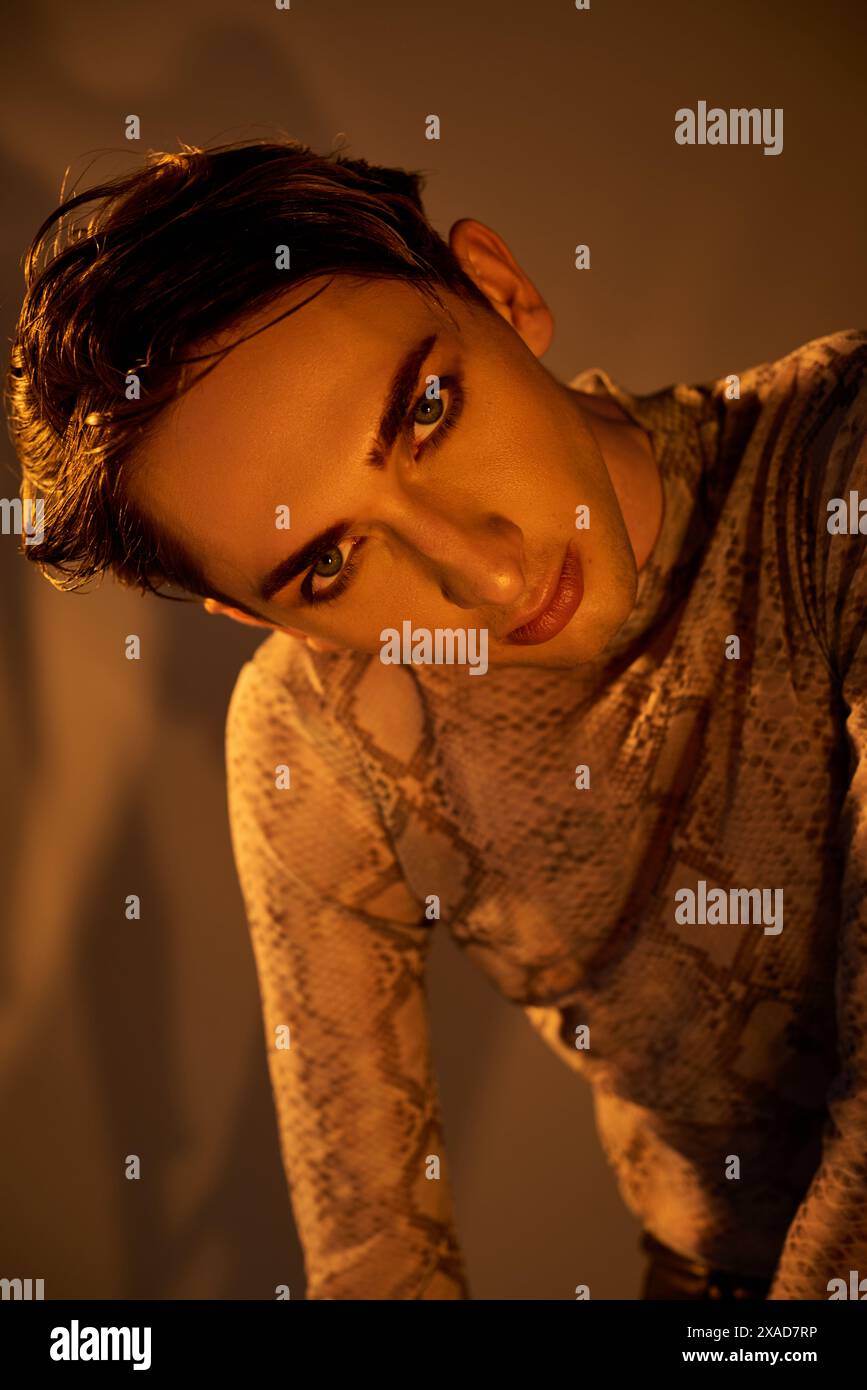 A stylish young queer man strikes a pose while wearing a snake skin ...