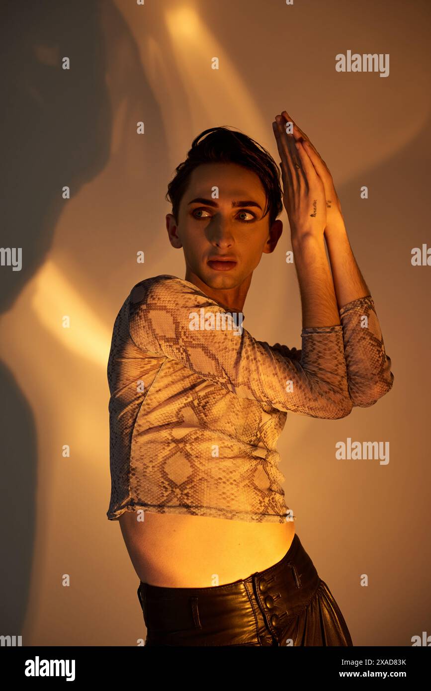 A young queer person in stylish attire strikes a confident pose with ...