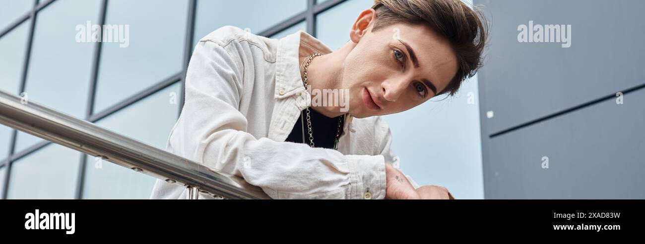 A stylish young queer person leaning against a railing, reflecting on ...