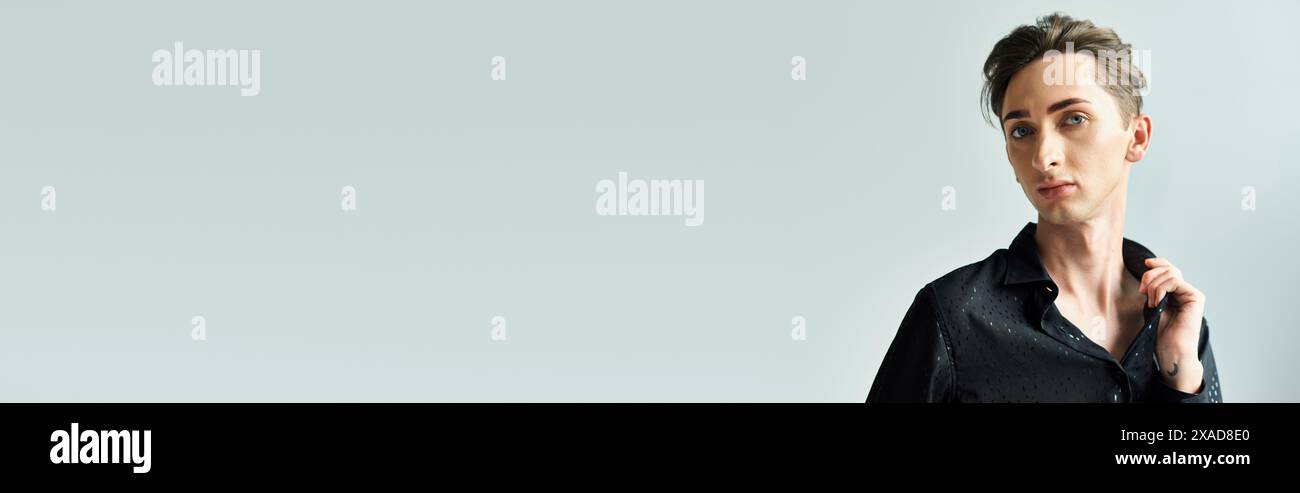 A young queer man confidently poses in a black shirt against a stark ...
