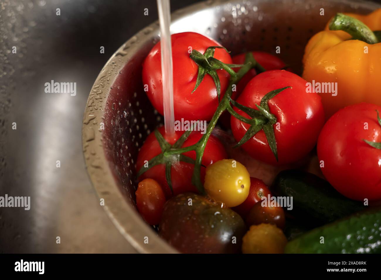 Washing different vegetables with tap water in metal colander inside ...